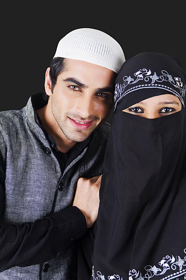 Muslim couple in-Traditional Clothes standing with arm-around looking ...