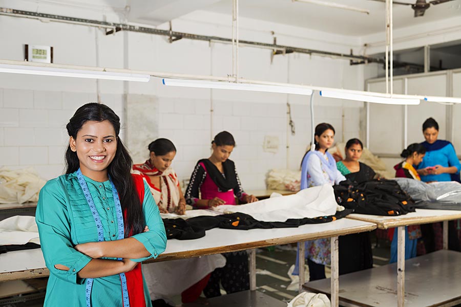 Woman Clothing Factory Supervisor Arms-Crossed Standing With Workers in ...